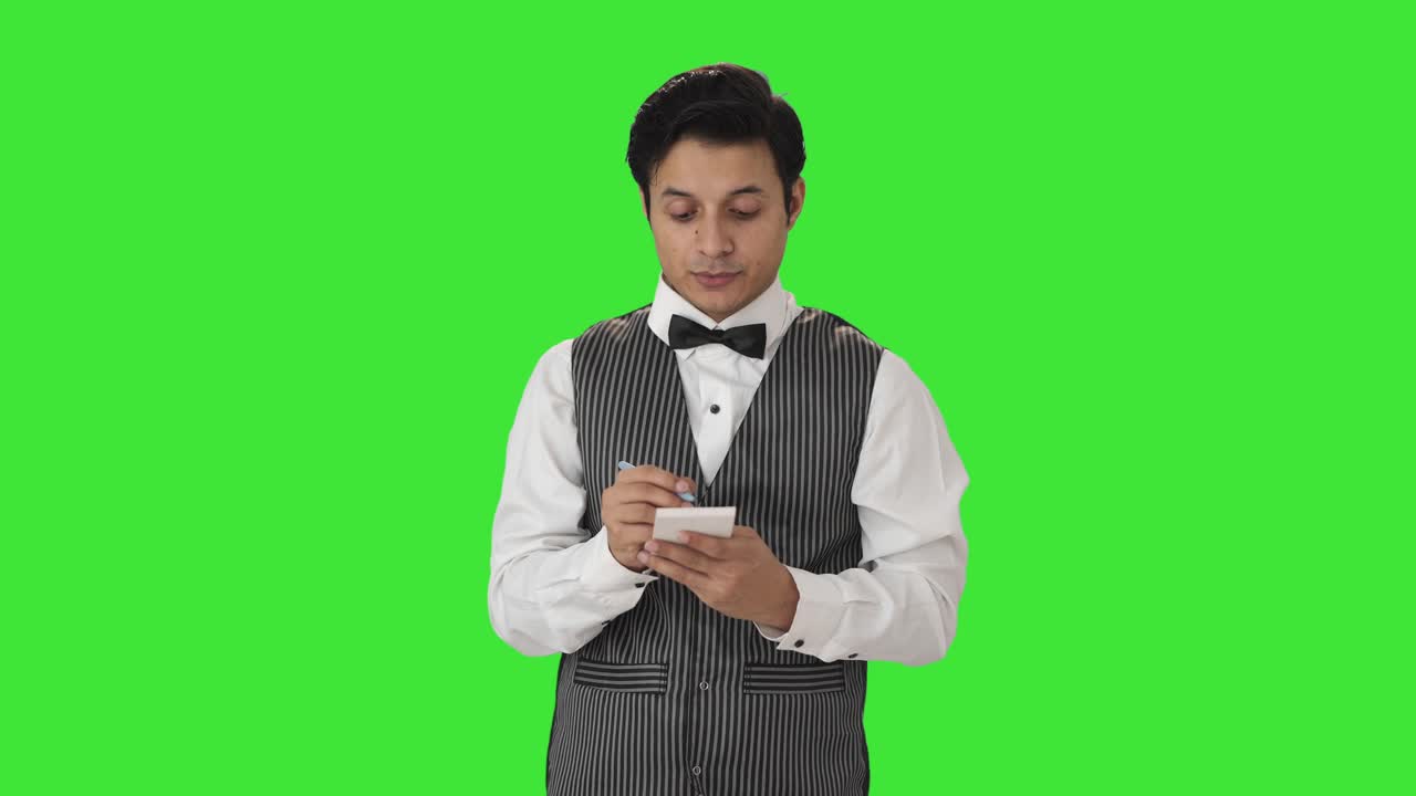 Premium stock video - Indian waiter taking order from customer green screen