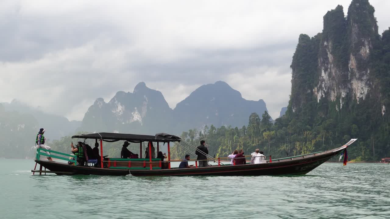 A longtail boat is sailing in Khao Sok National Park in Thailand with ...