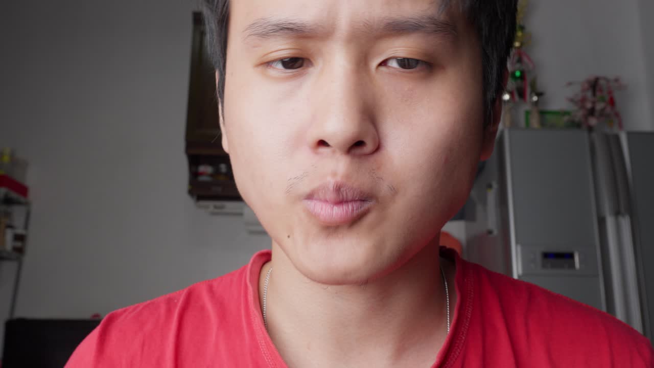 Premium stock video - Man in red shirt enjoying a quick snack indoors, close-up