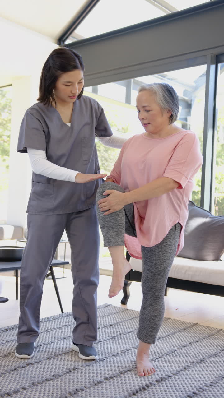 Vertical video: Physical therapist assisting senior woman with leg ...