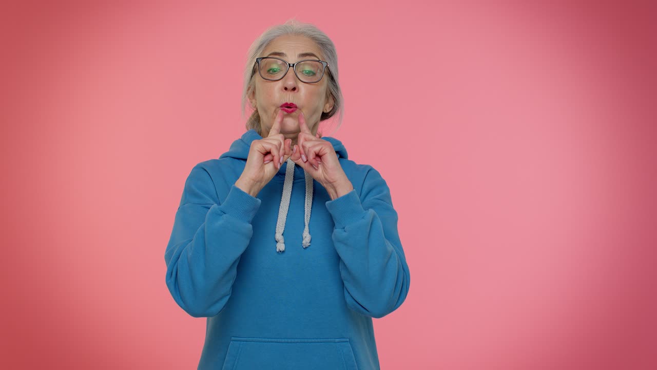 Senior old granny woman pointing around with finger gun gesture ...