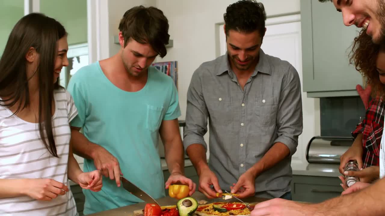 Premium stock video - Smiling friends making pizza together