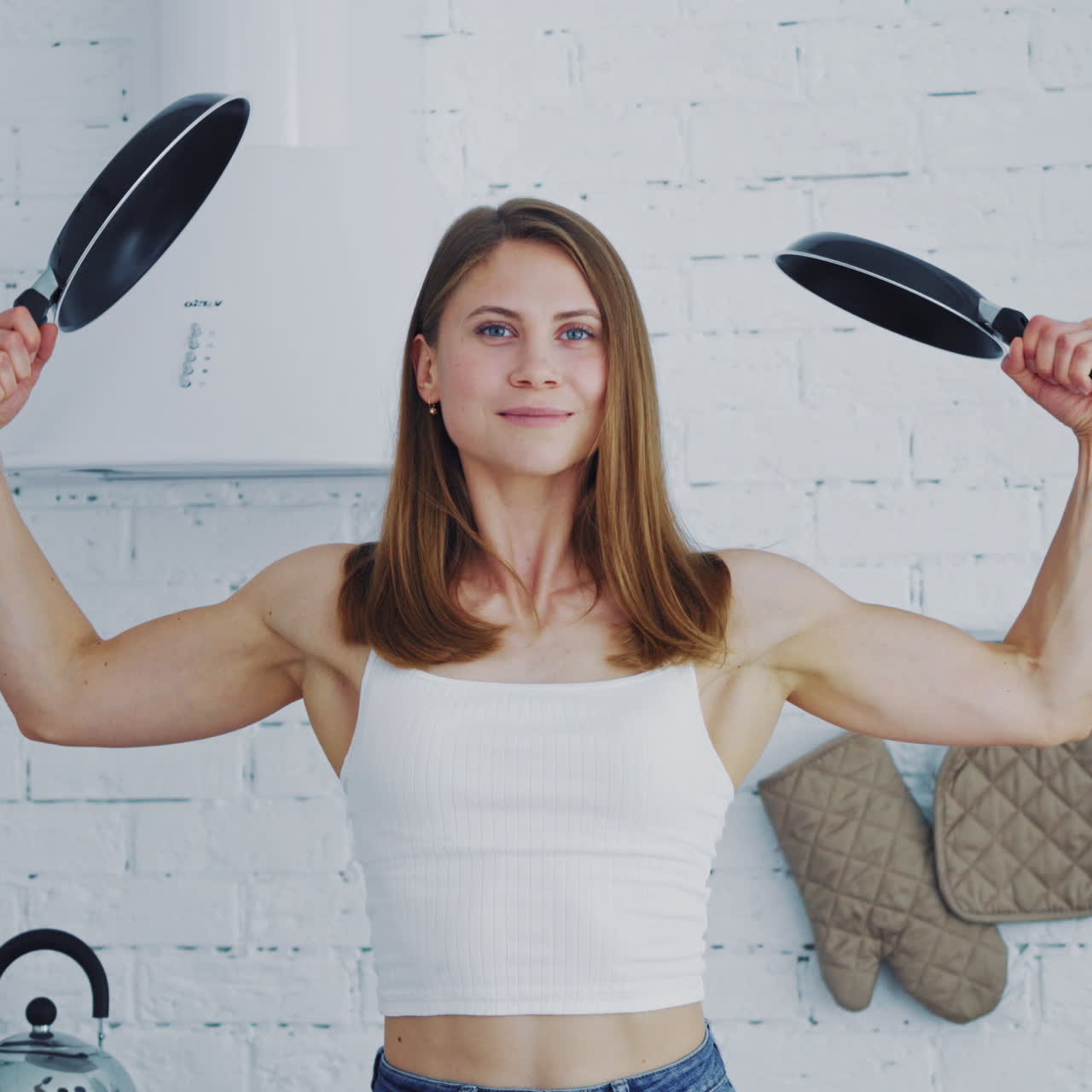 Pretty female with frying pans at home. Muscular young woman holding ...