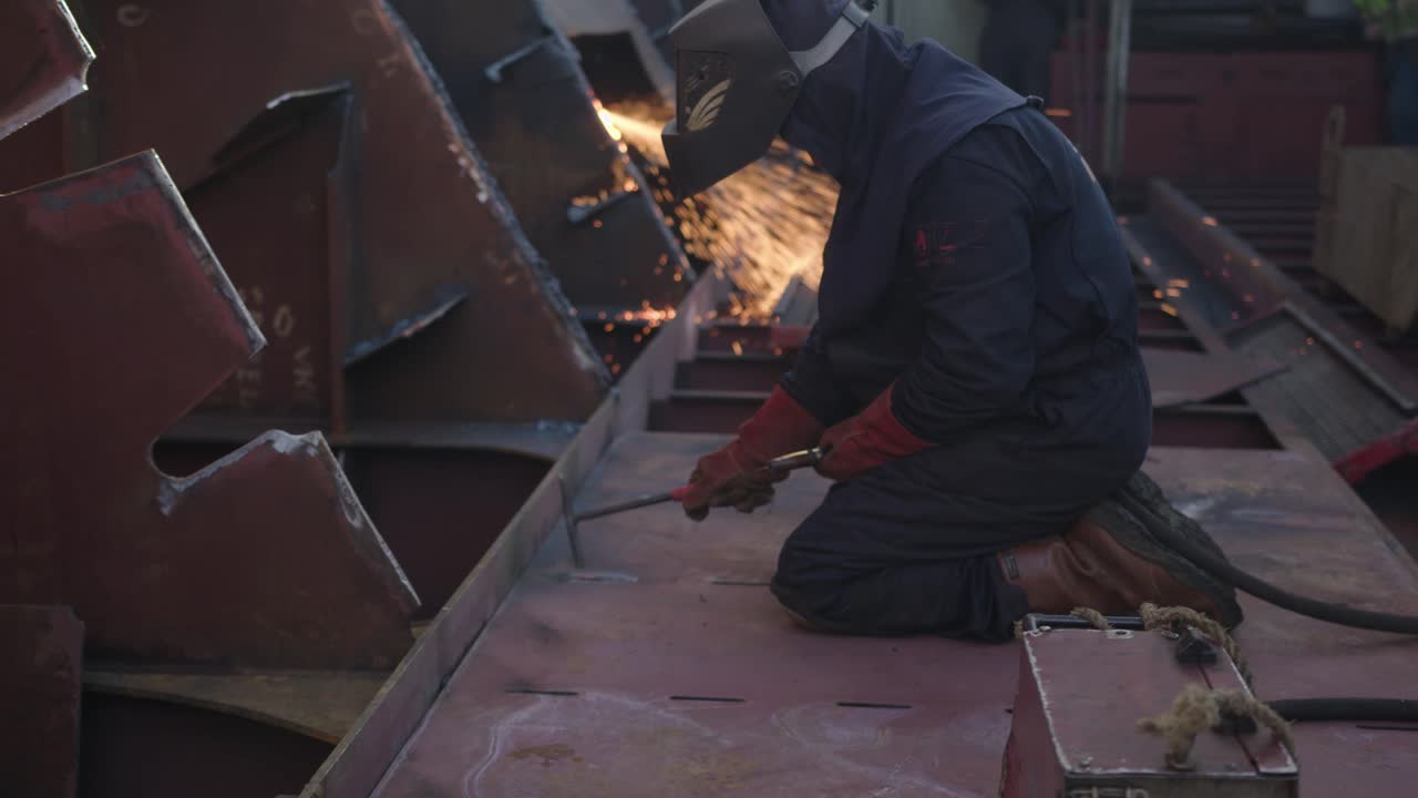 Premium stock video - Man working on a cargo ship is hammering a spot ...