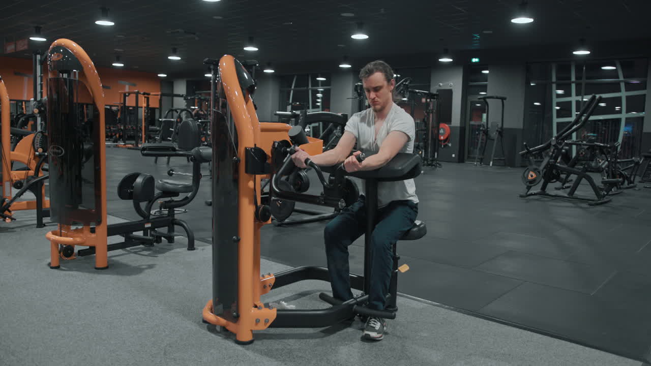 Man on bicep curl machine exercise arms heavy weights in indoor gym ...