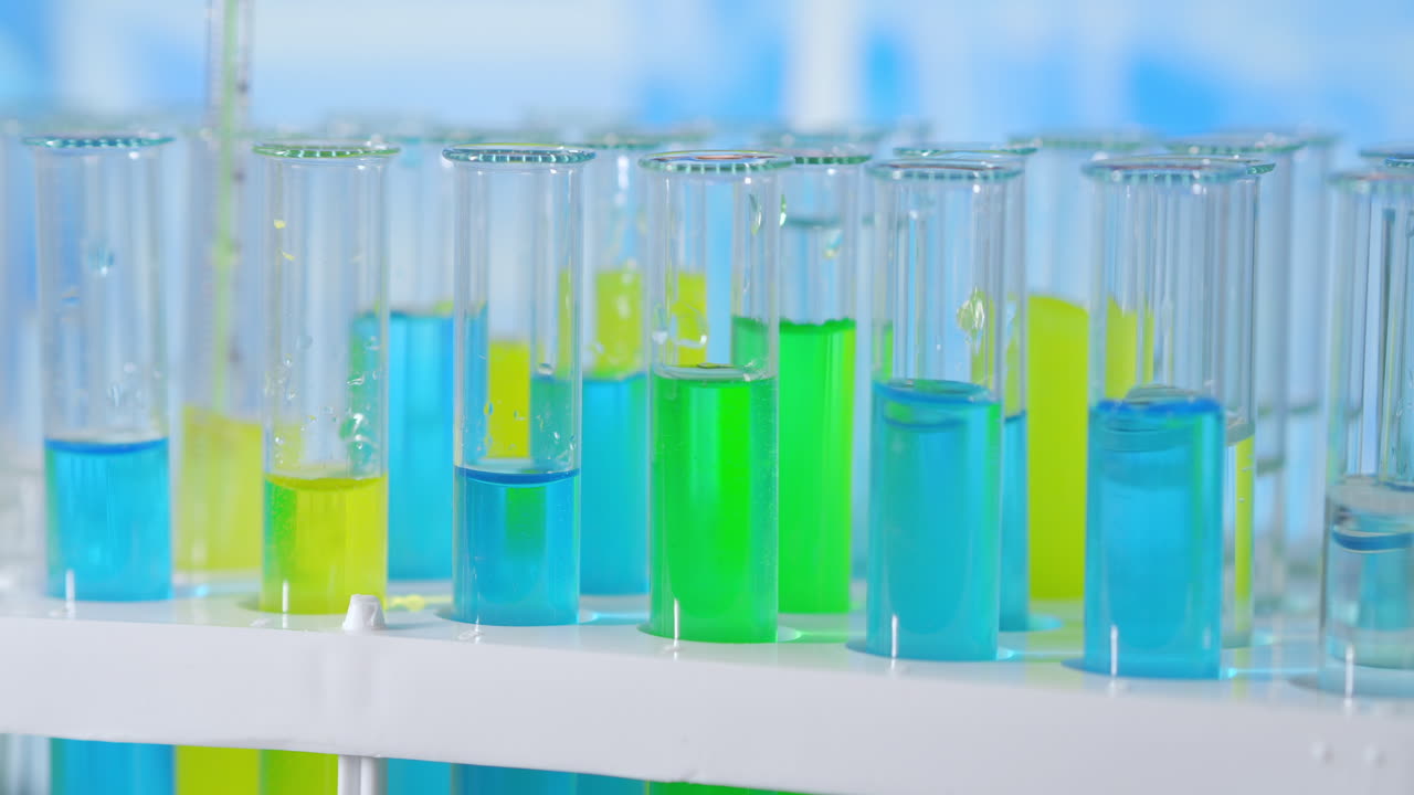 In a laboratory a scientist with a pipette analyzes a colored liquid to ...