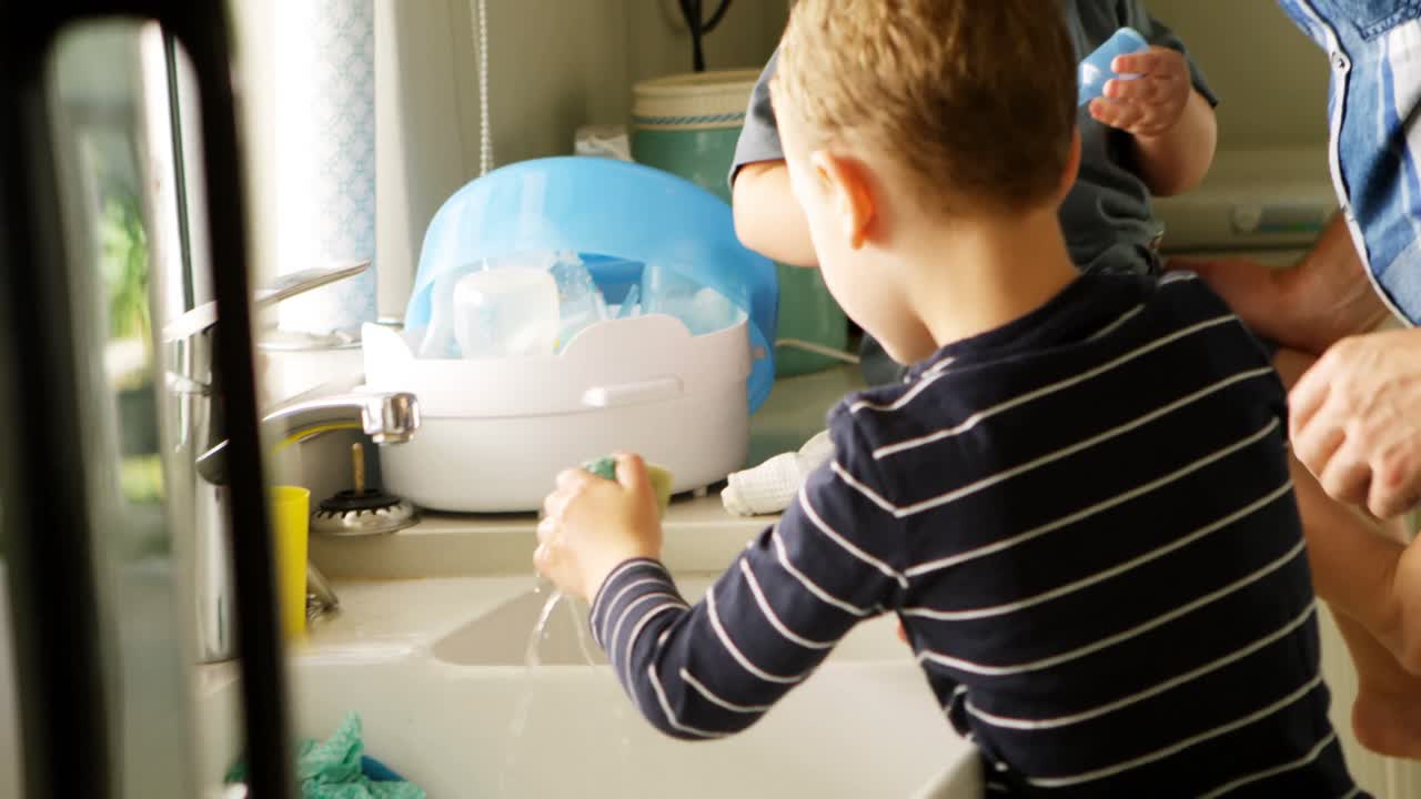 Father and siblings cleaning kitchen sink 4k | Premium Stock Video Footage