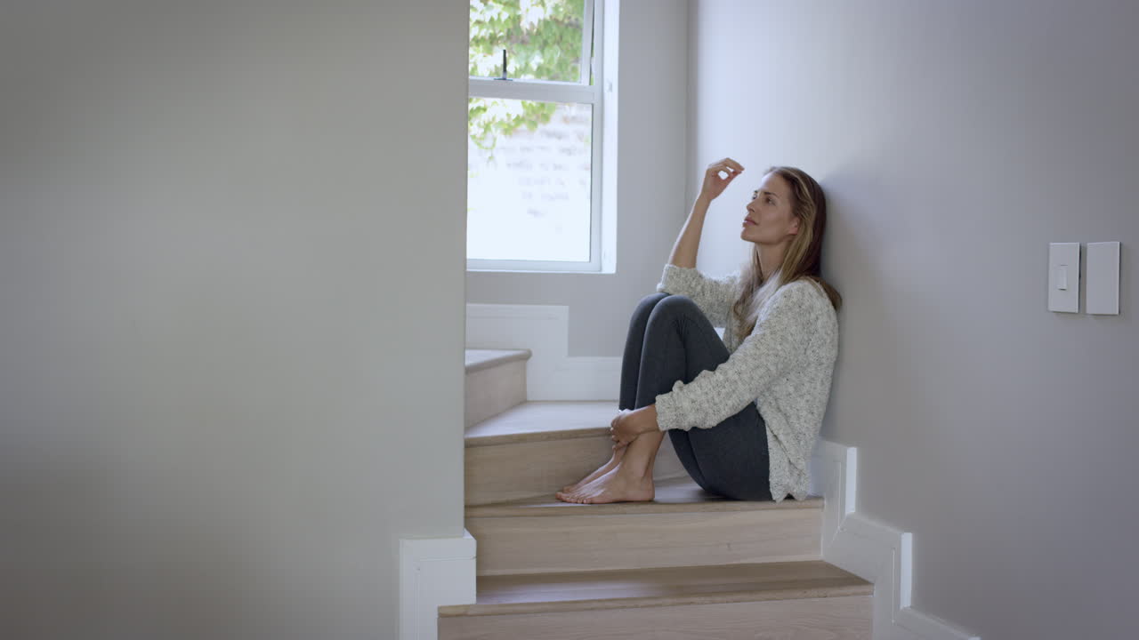 Sad young woman crying on step at home has a broken heart is overcome ...