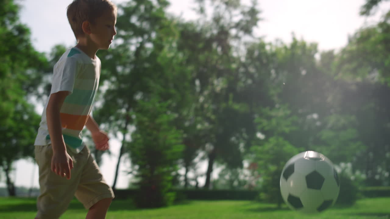 Premium stock video - Active boy kick ball on green grass. little ...