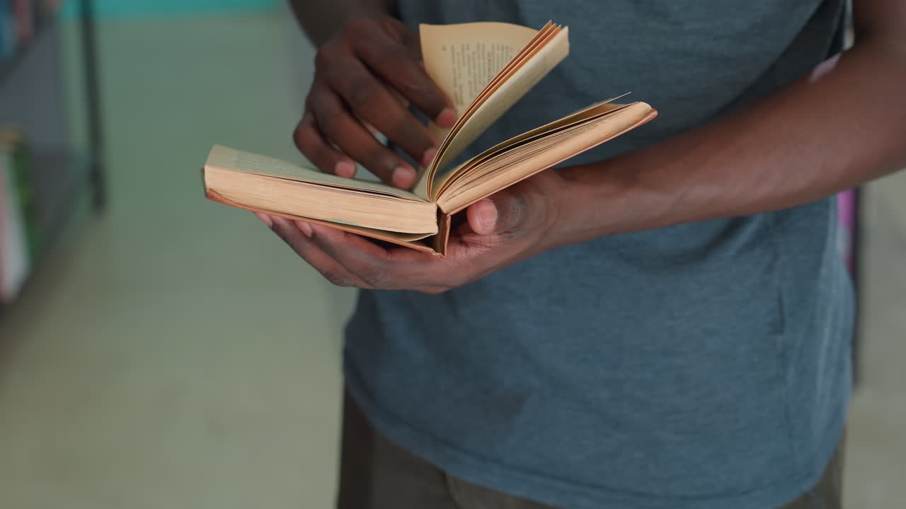 Close up of adult flipping through pages of vintage book while standing ...