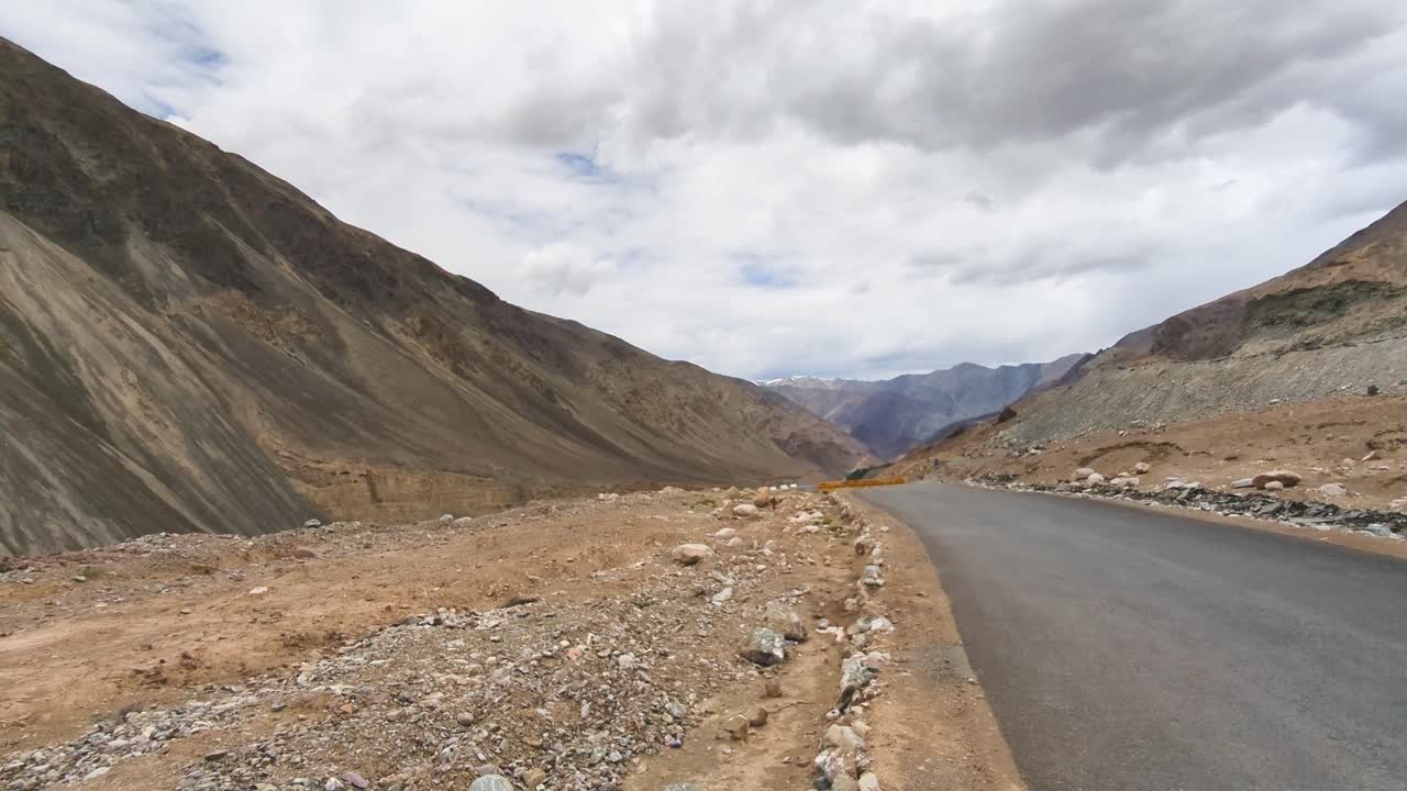 Pan shot of a road through himalayan mountains landscape in barren cold ...
