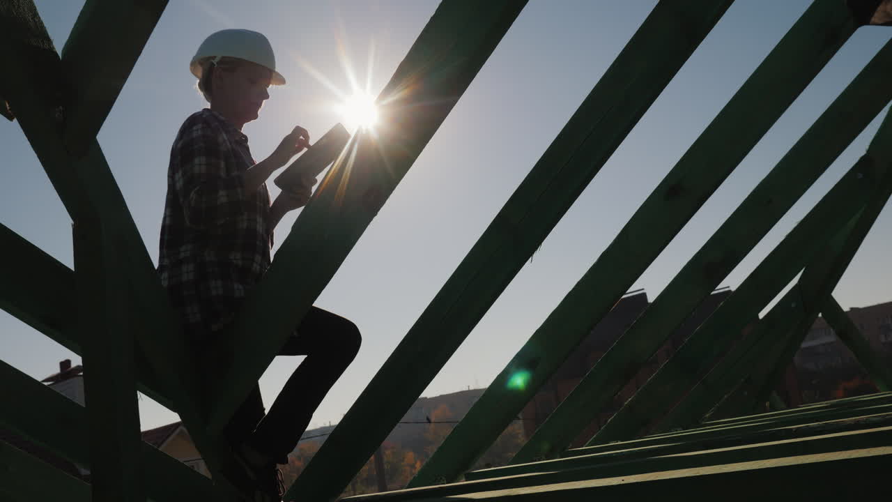 Silhouette of an engineer works among the rafters of the roof uses a ...