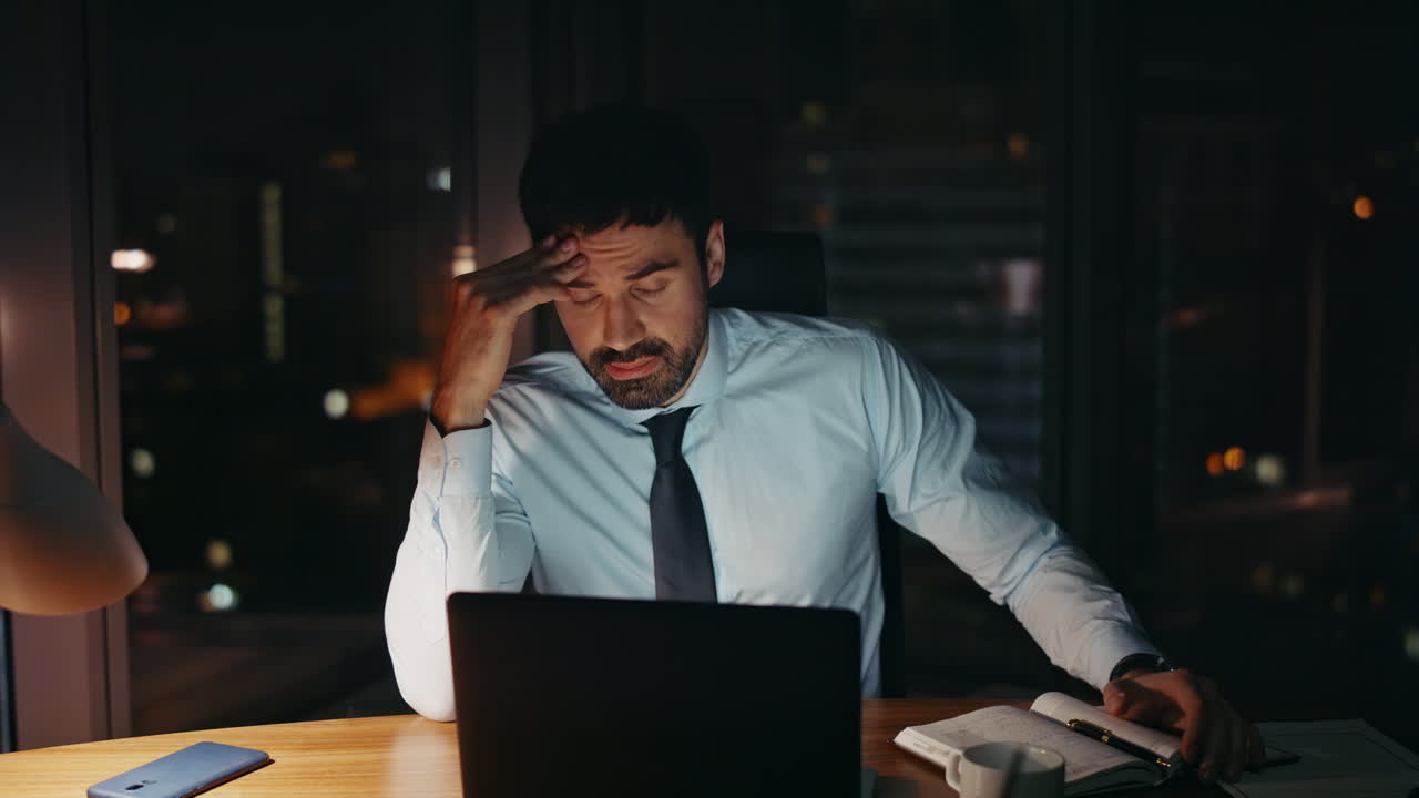 Stressed late worker sitting workplace looking laptop close up. Worried ...