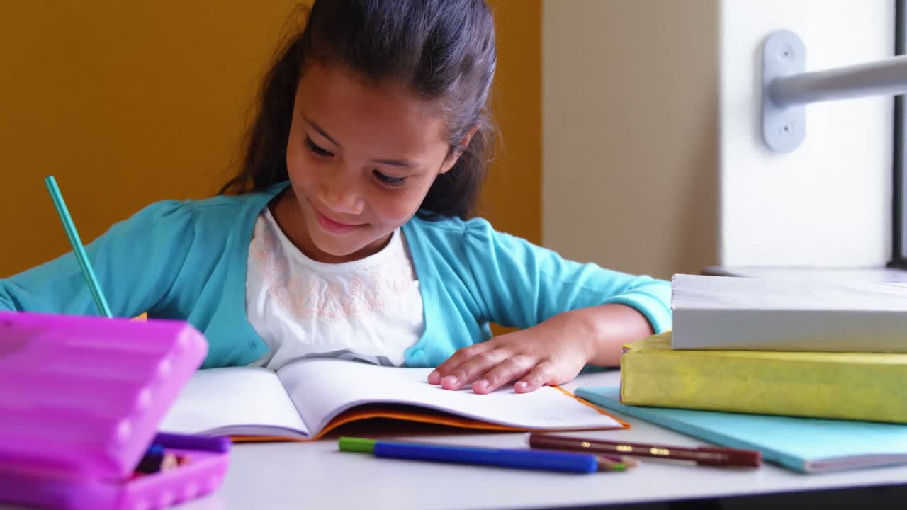 Premium stock video - Schoolgirl doing homework in classroom at school
