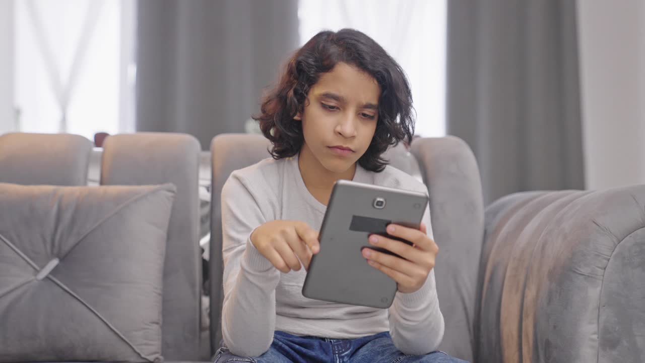 Premium stock video - Indian kid using and scrolling through tablet