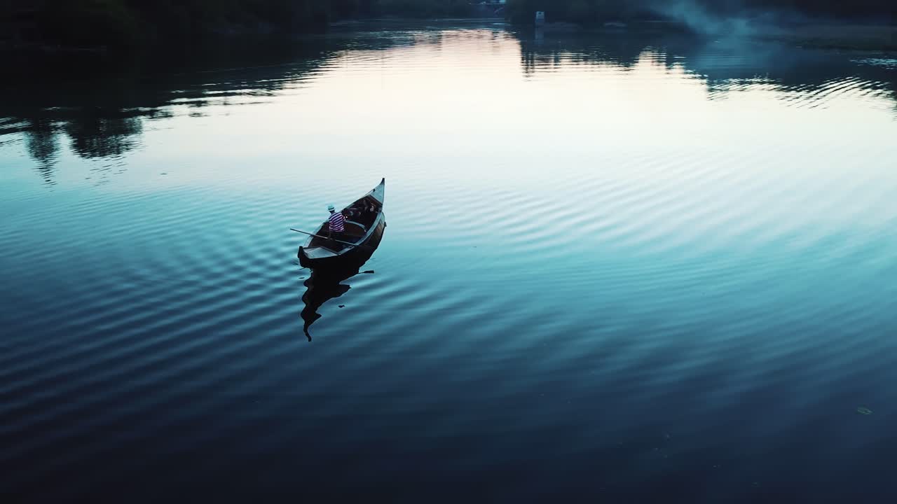 Aerial view of a luxurious woman floating in a boat on a river at night ...