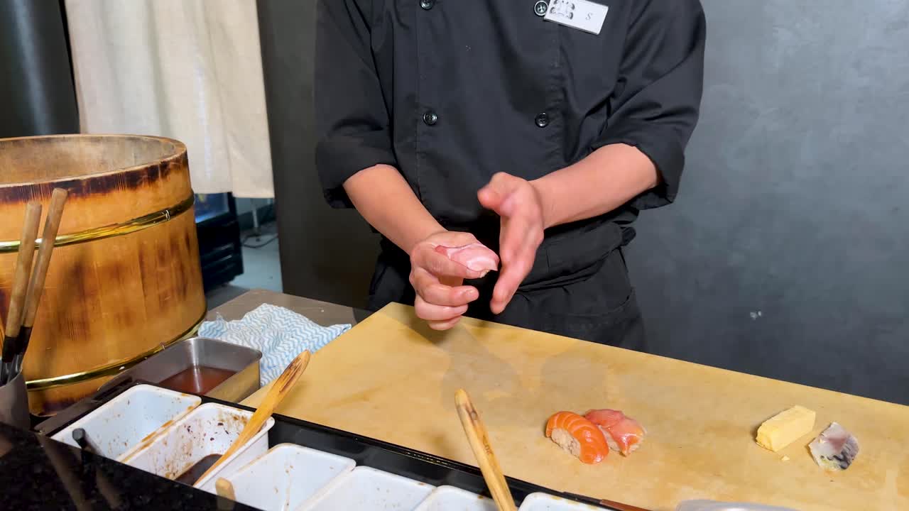 Close-up shot of a chef's hands skillfully shaping rice and fish for ...