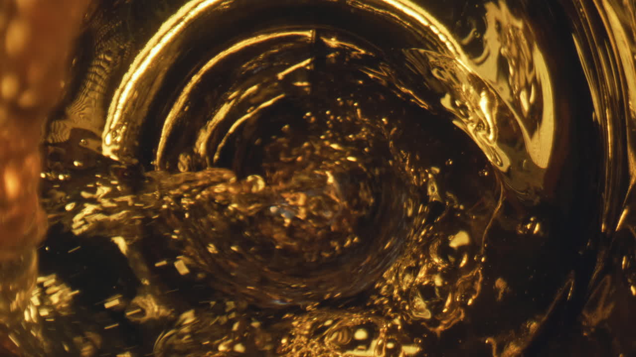 Golden liquid flowing goblet closeup. Golden lager beer waving inside ...