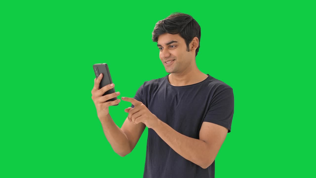 Premium stock video - Young indian boy using dating app green screen