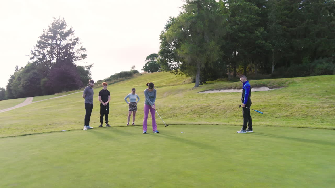 Golf players playing golf together, hitting the ball with club on a ...