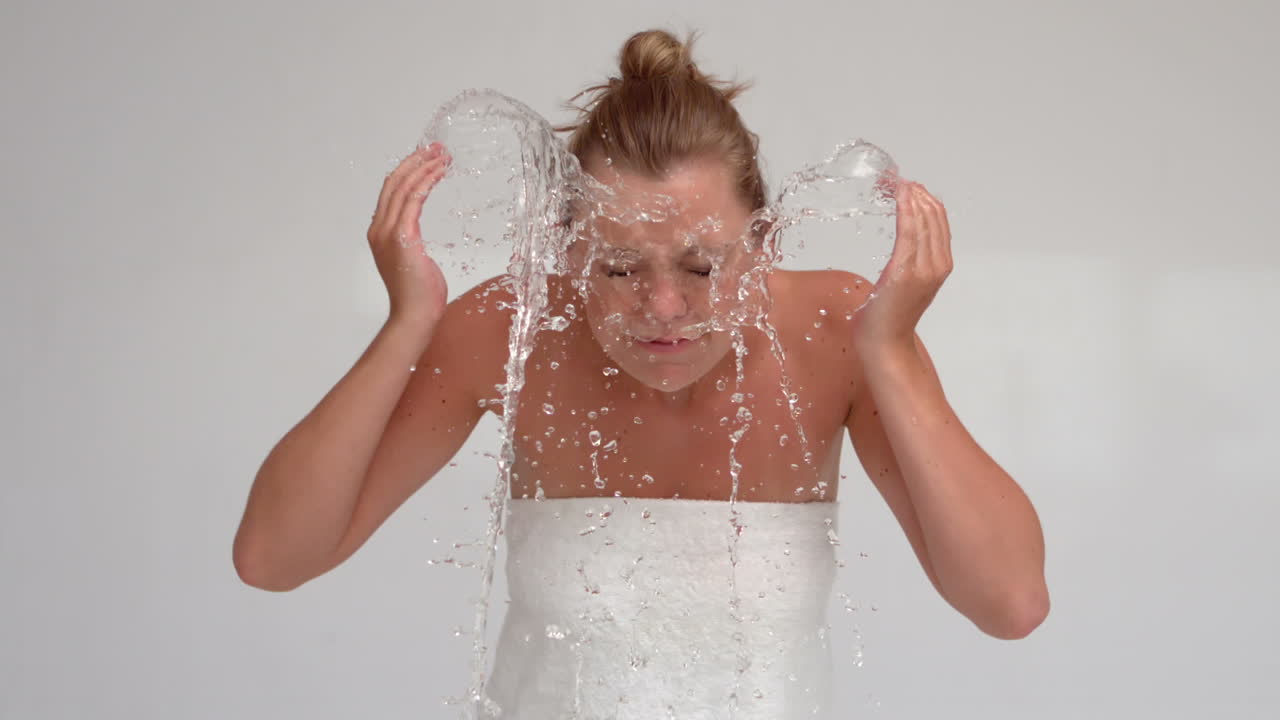 Premium stock video - Woman splashing water on her face