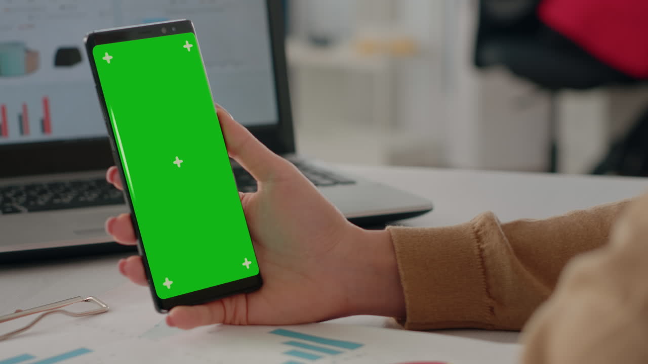 Close up of hand holding green screen vertically on mobile phone ...