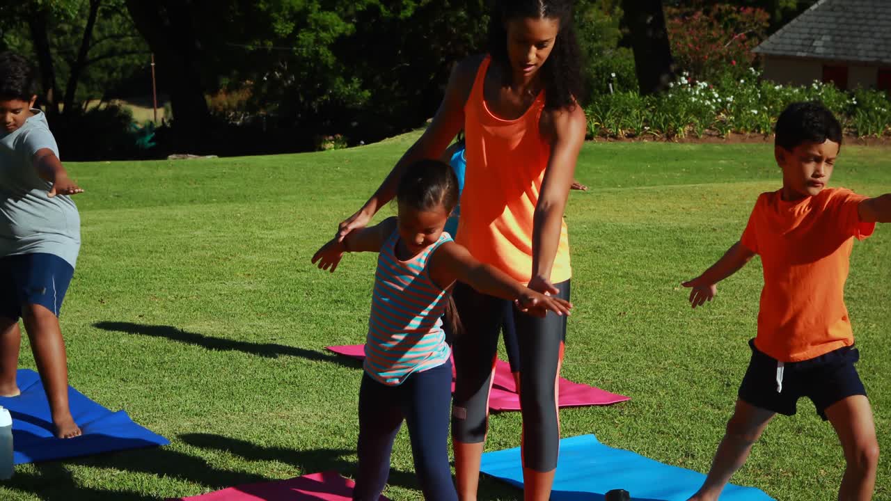 Yoga instructor instructing children in performing exercise Premium ...