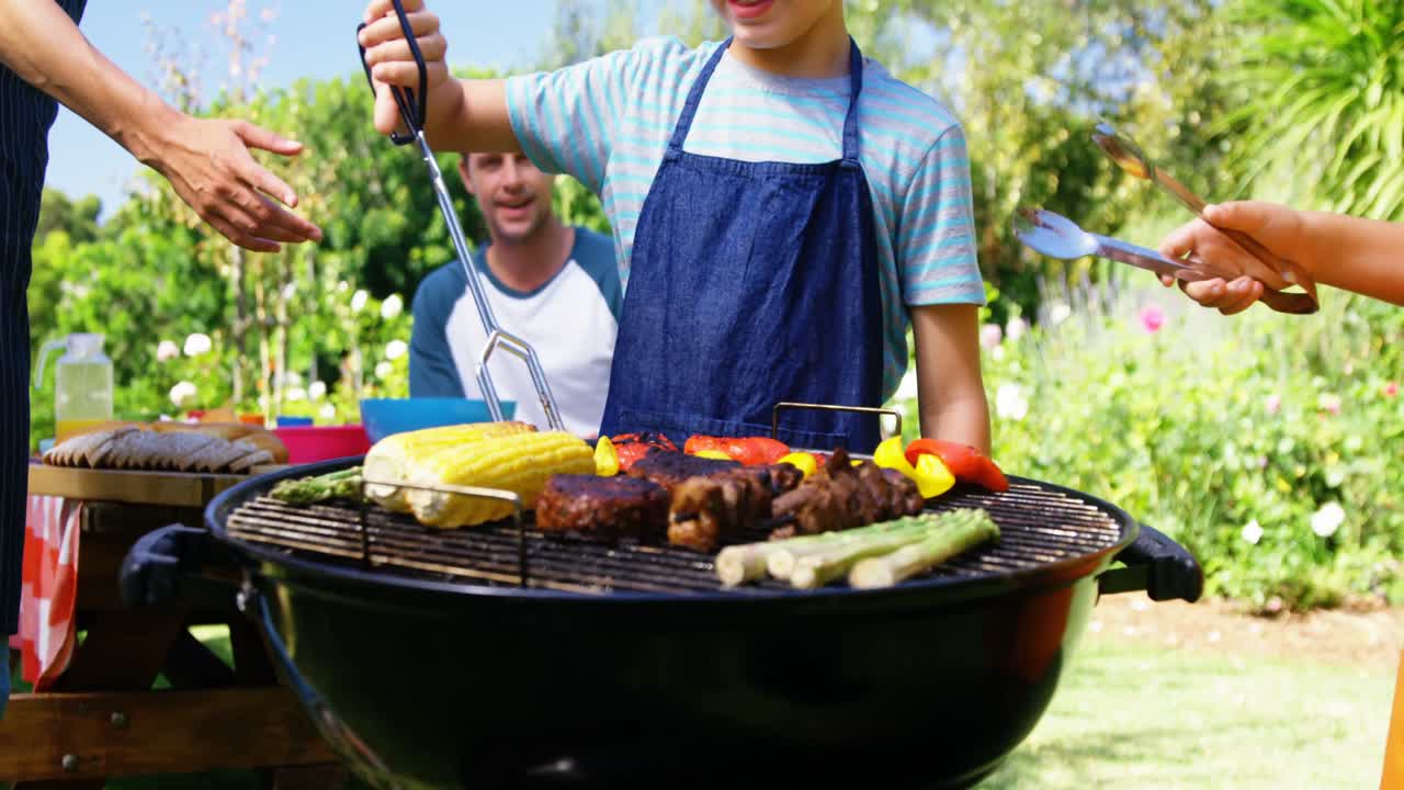 Premium stock video - Kids grilling meat and vegetables on barbecue
