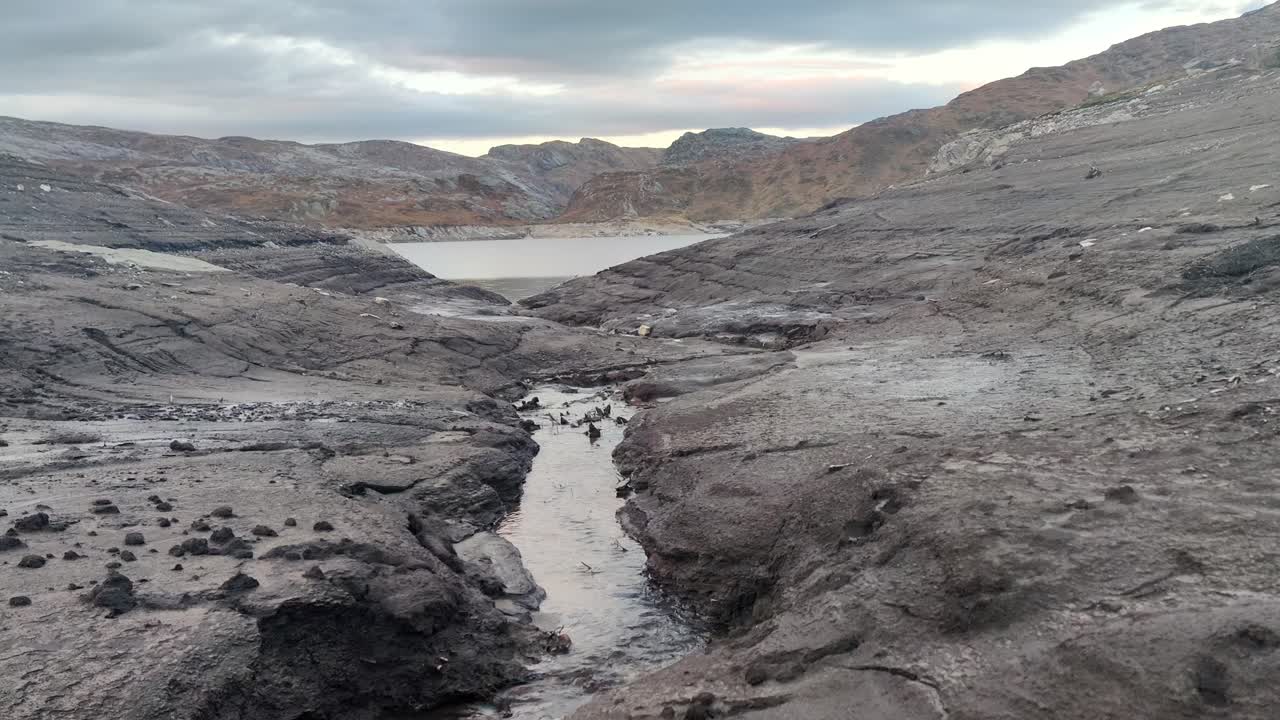 Small stream of water flows into almost empty water reservoir for ...