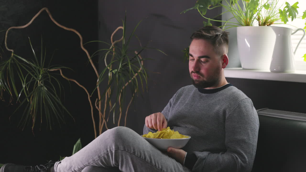 Free stock video - Hungry man sitting on sofa and eating delicious ...