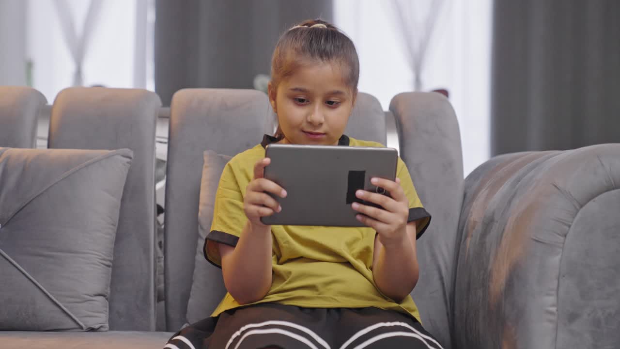 Premium stock video - Indian girl kid using and scrolling through tablet