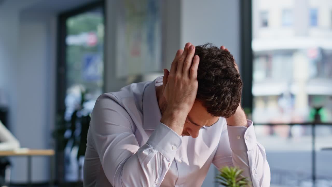 Exhausted businessman thinking problem holding head at office workplace ...