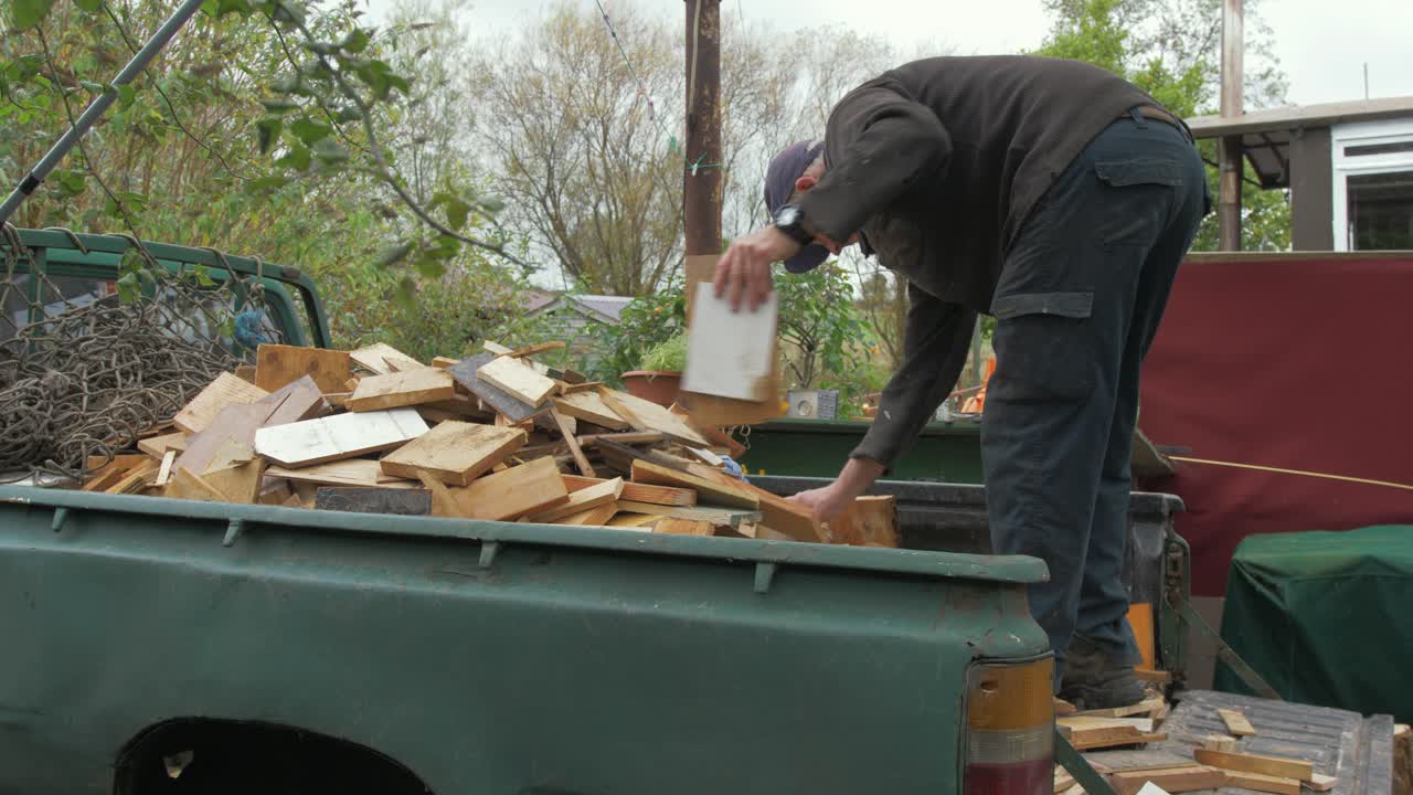 Premium stock video - Mature man unloading a truckload of scrap timber