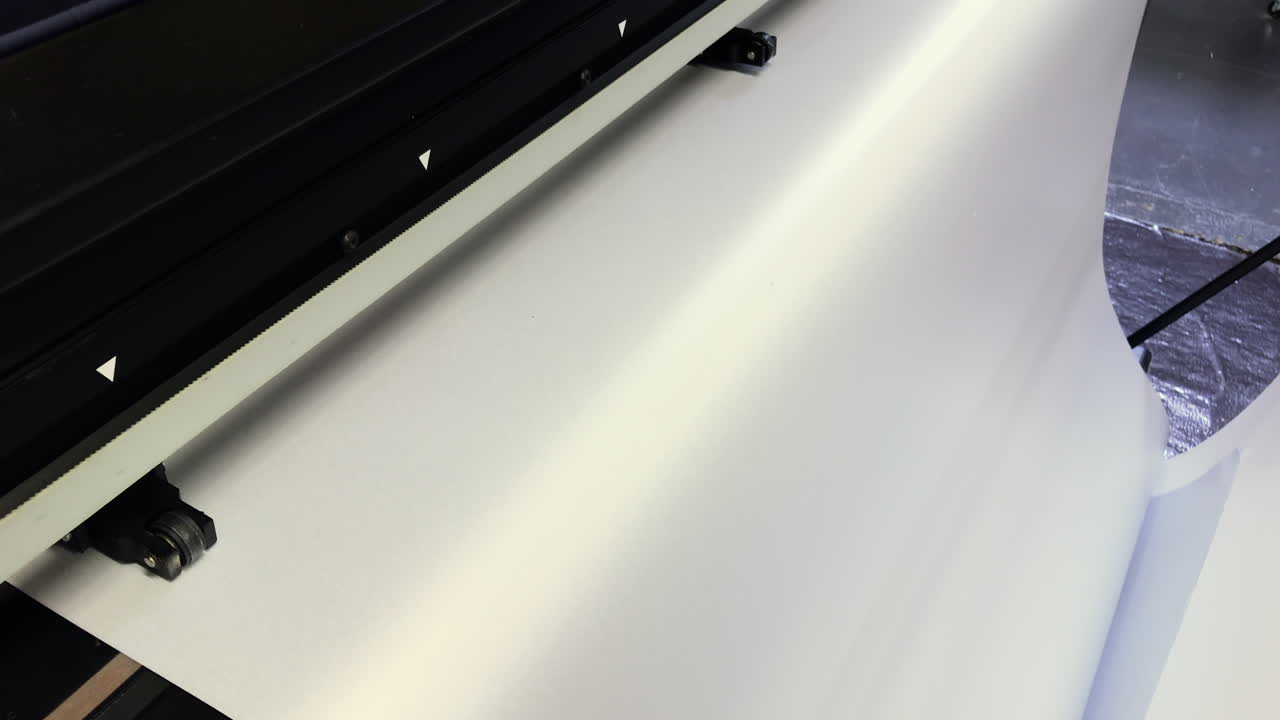 Premium stock video - A cutting plotter cuts of a sheet of white vinyl