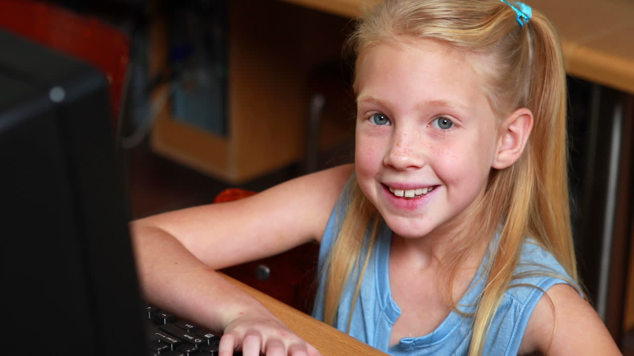 Premium stock video - Little girl smiling at camera during computer class