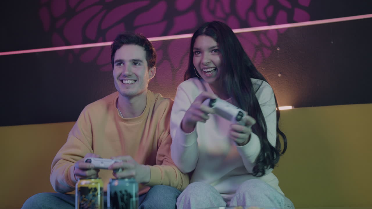 Two Friends Playing Video Games Sitting On Sofa At Home 1 Free Stock ...