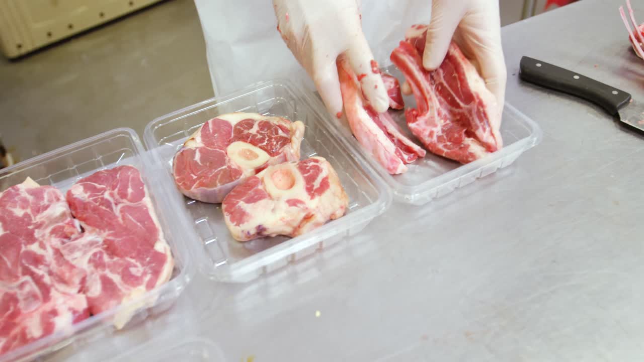 Premium stock video - Mid section of butcher packing red meat in container