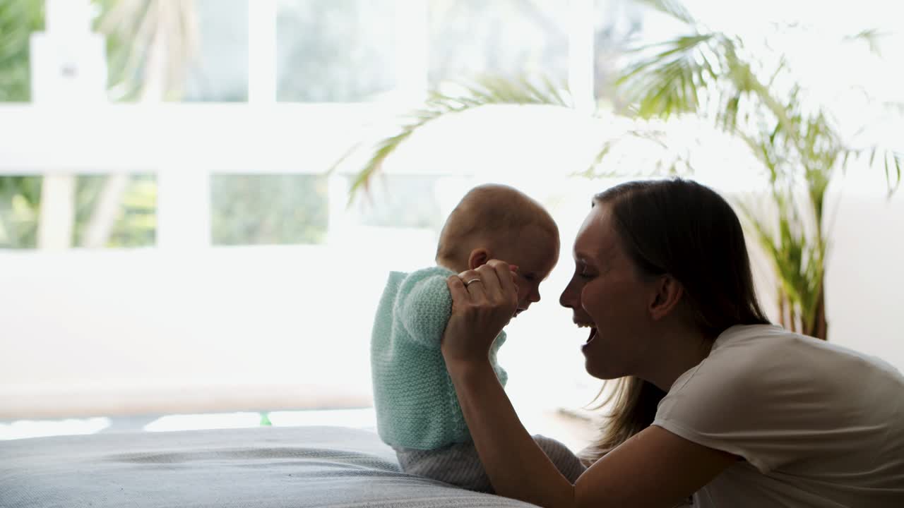 Premium stock video - Joyful excited mom helping baby daughter to sit up