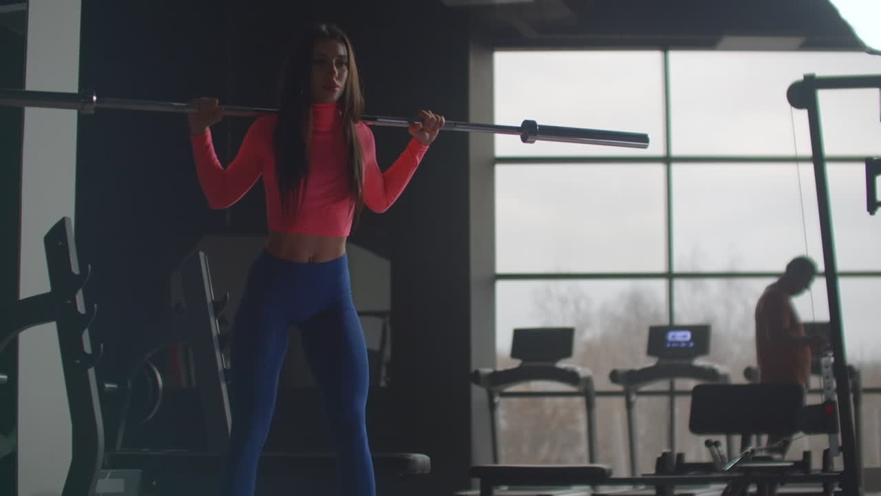 The Woman Slowly Crouches With A Barbell On Her Shoulders. She Pumps ...