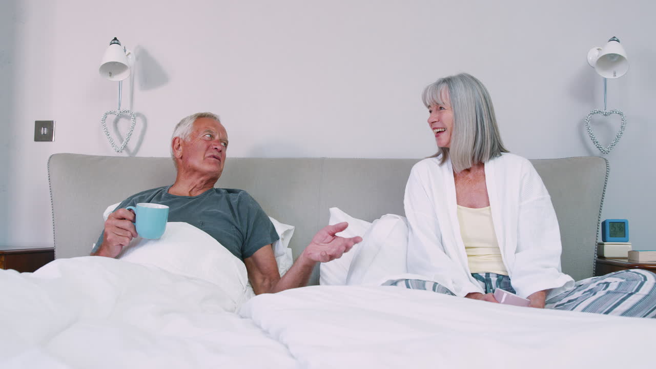 Retired couple wearing pajamas sitting in bed drinking tea Premium ...