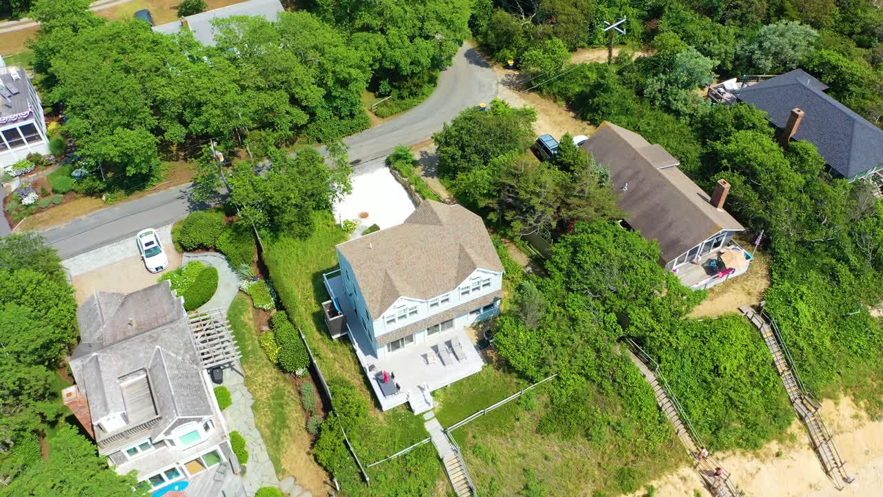 Drone orbit of a Cape Cod beach house with sandy shoreline below ...
