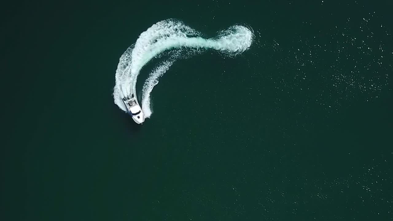 Aerial bird view of a speedboat riding in a circle and making beautiful ...
