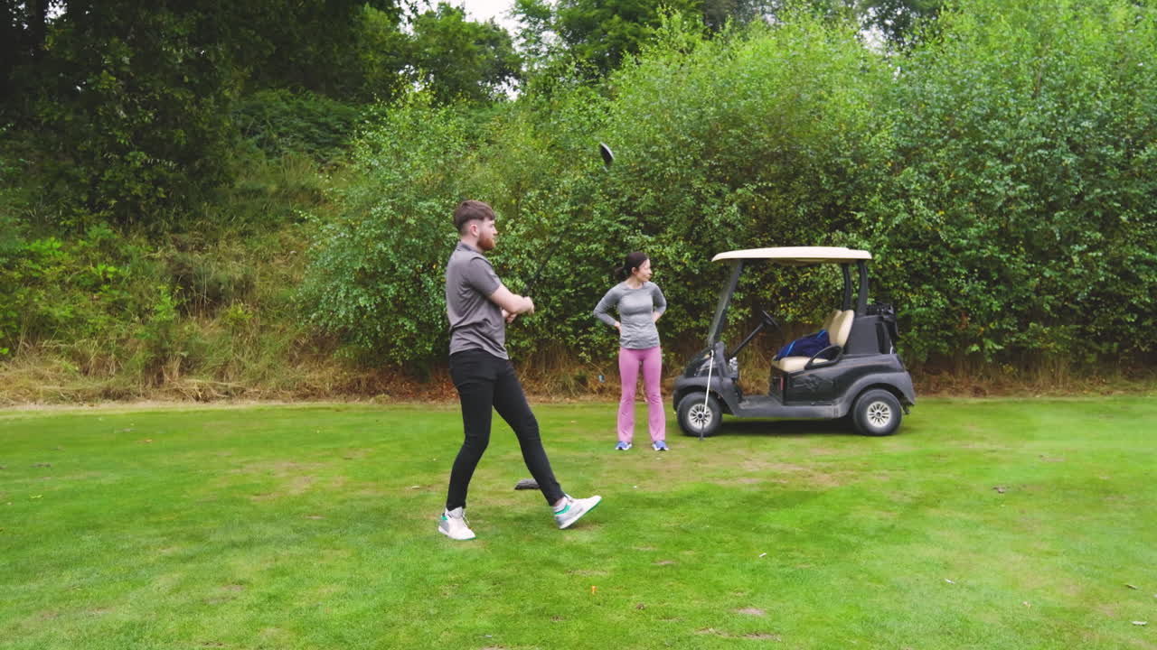 Two male and female golf players playing golf together, hitting the ...