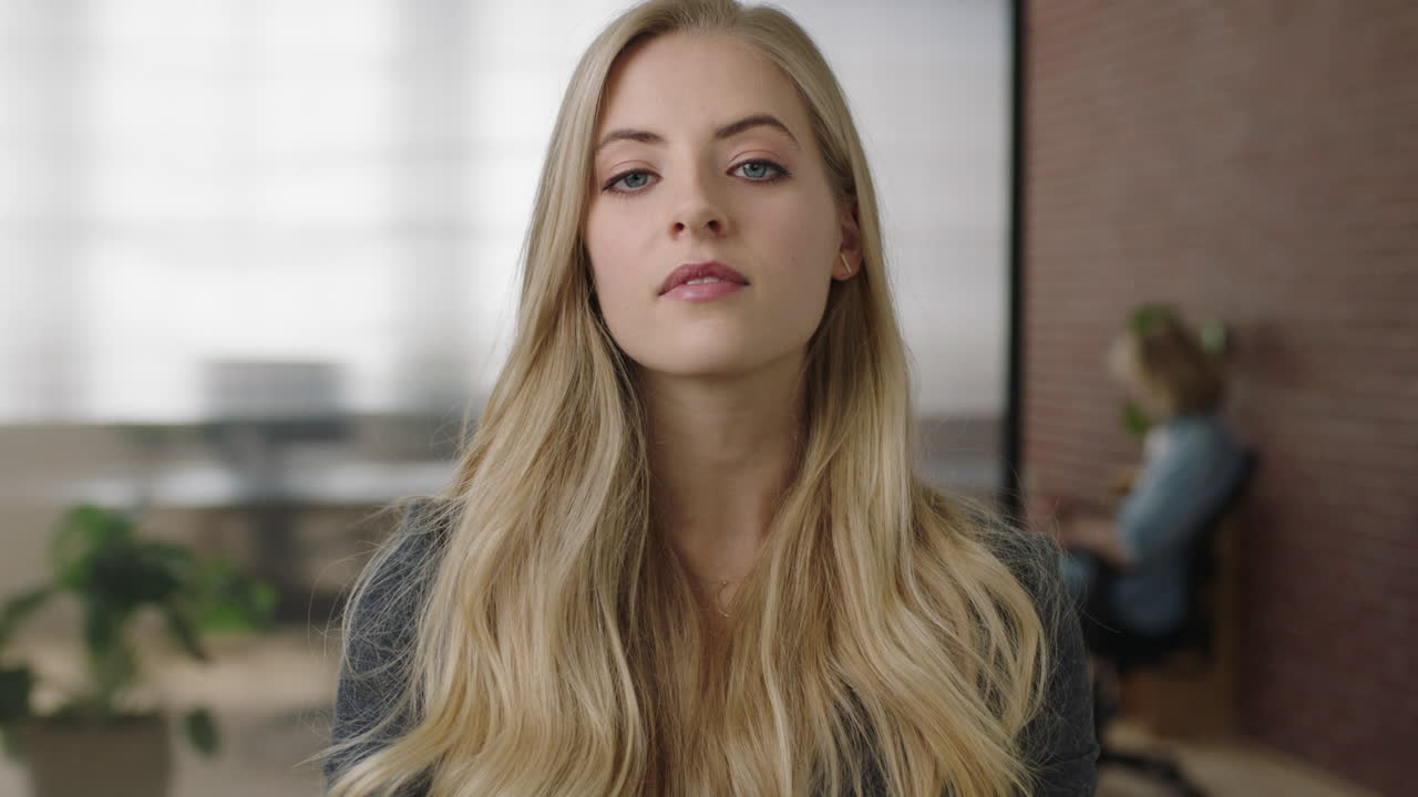 Portrait of confident young blonde woman executive running hand through ...