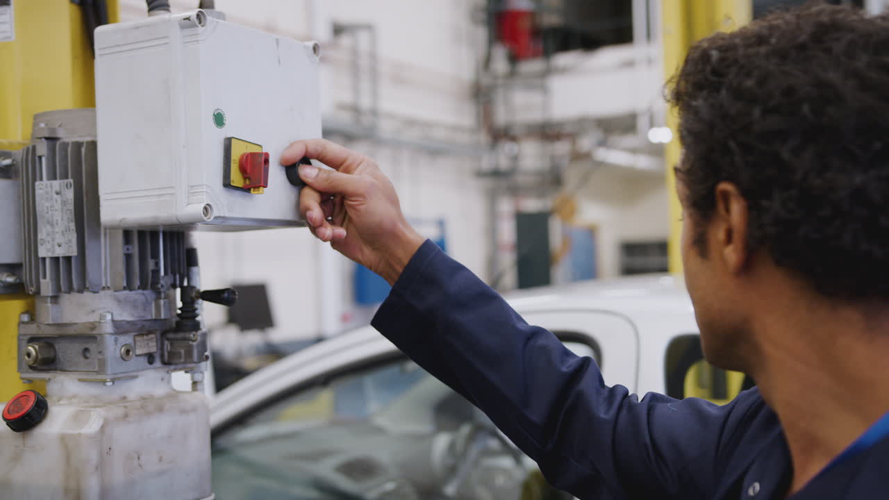 Premium stock video - Male motor mechanic raising car on hydraulic lift ...