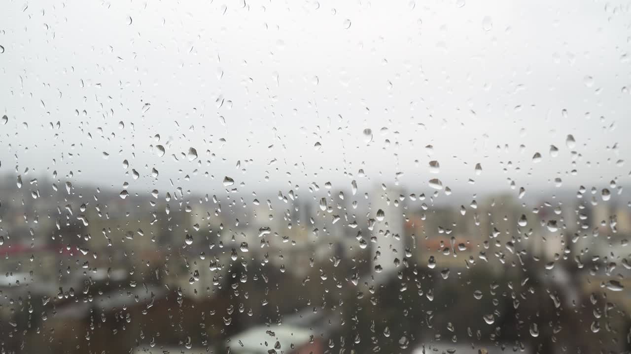 Raindrops run down the glass outside the window. Gloomy sky in cloudy ...