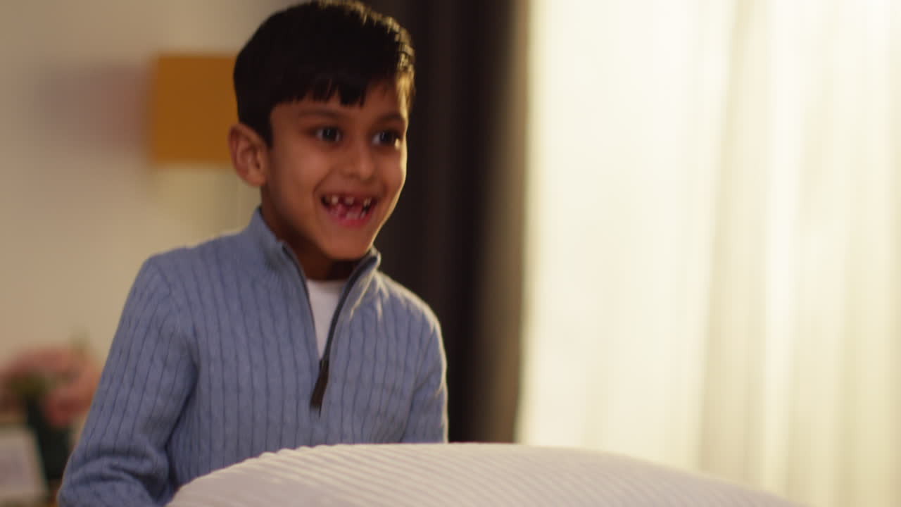 Disruptive young boy behaving badly at home jumping on sofa and ...