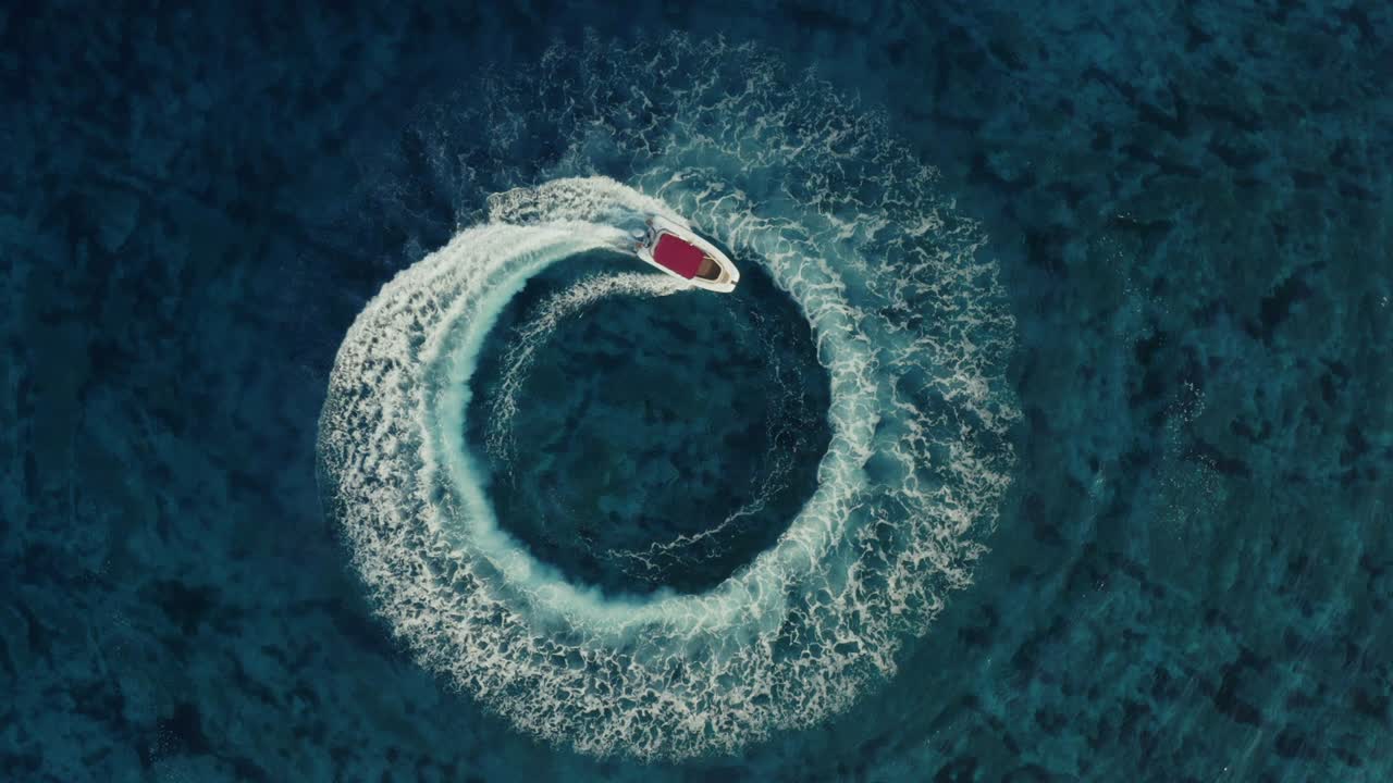 Slow motion aerial shot descending towards fast speedboat with a red ...