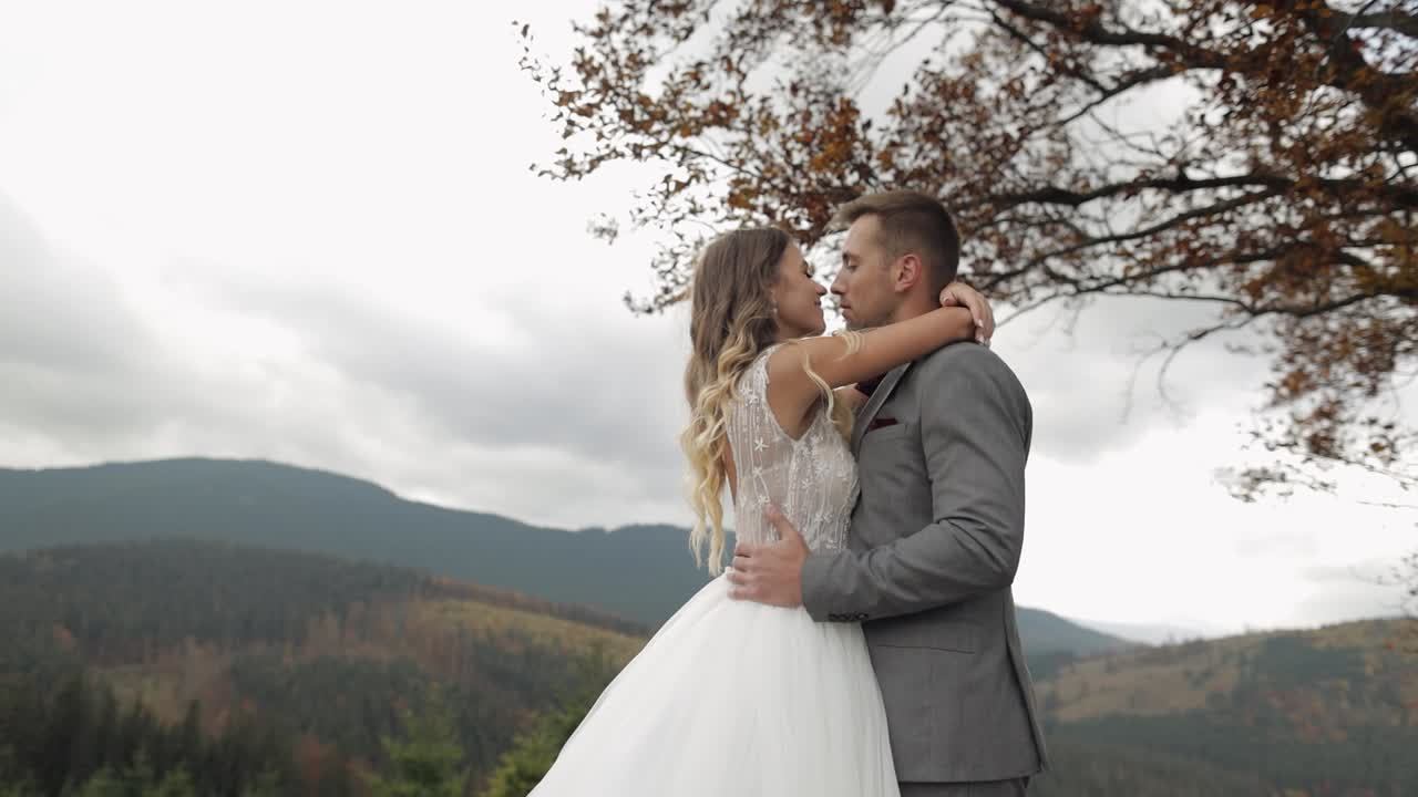 Lovely young newlyweds bride groom embracing on mountain slope, happy ...