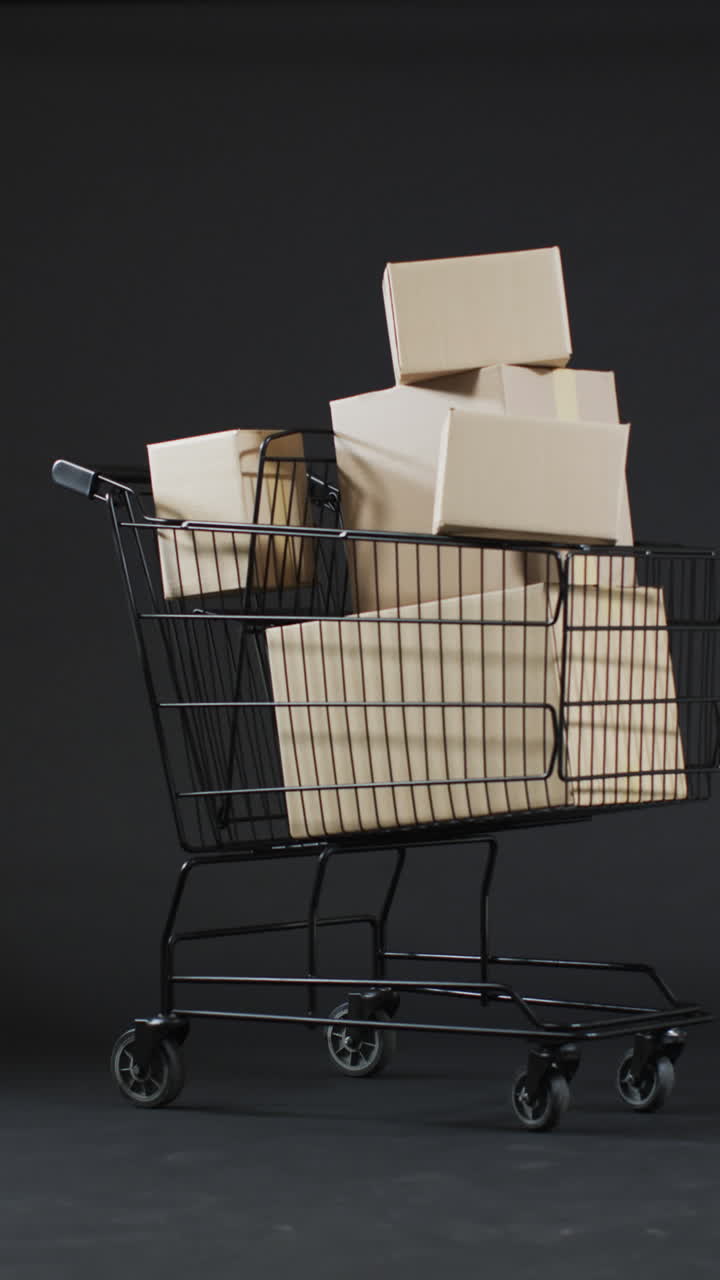 Vertical video of shopping trolley with boxes and copy space over grey ...